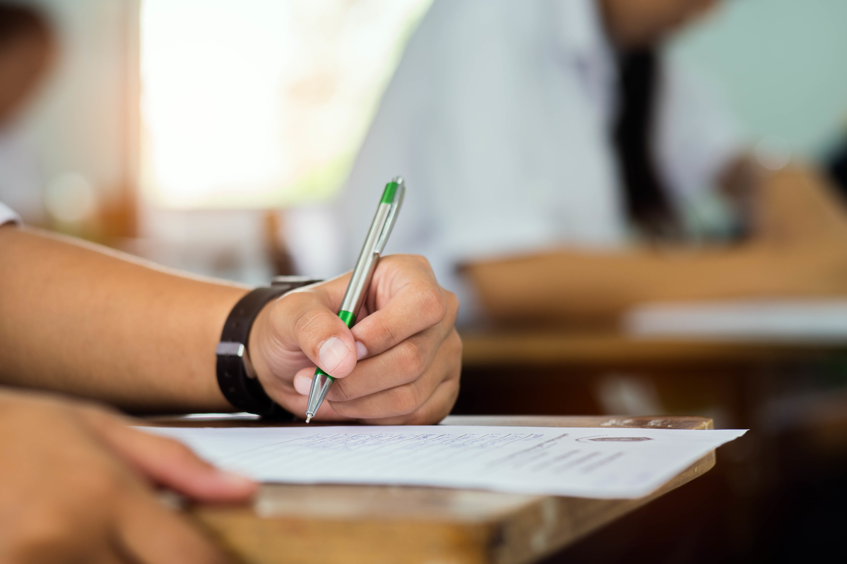 Students writing and reading exam answer sheets exercises in classroom ...